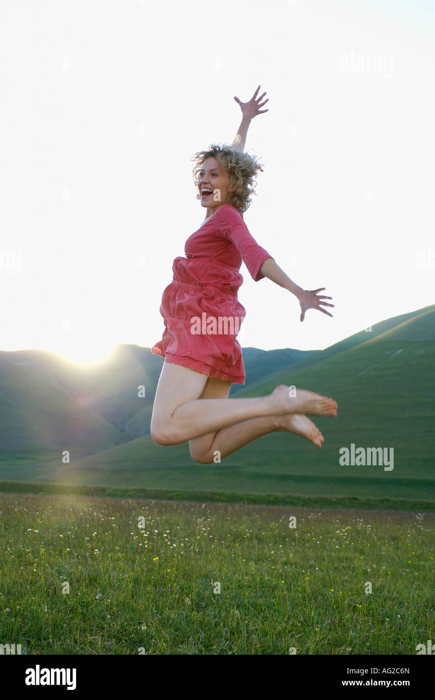Woman jumping for joy in mountain meadow, side view Stock Photo - Alamy