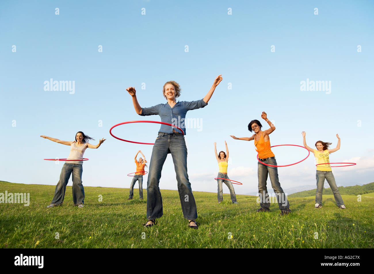 Group of friends using hula hoops in mountain field, low angle view ...
