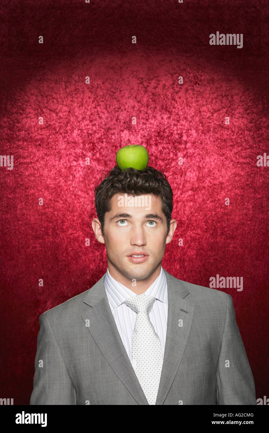 Man with apple on head against red velvet background Stock Photo - Alamy