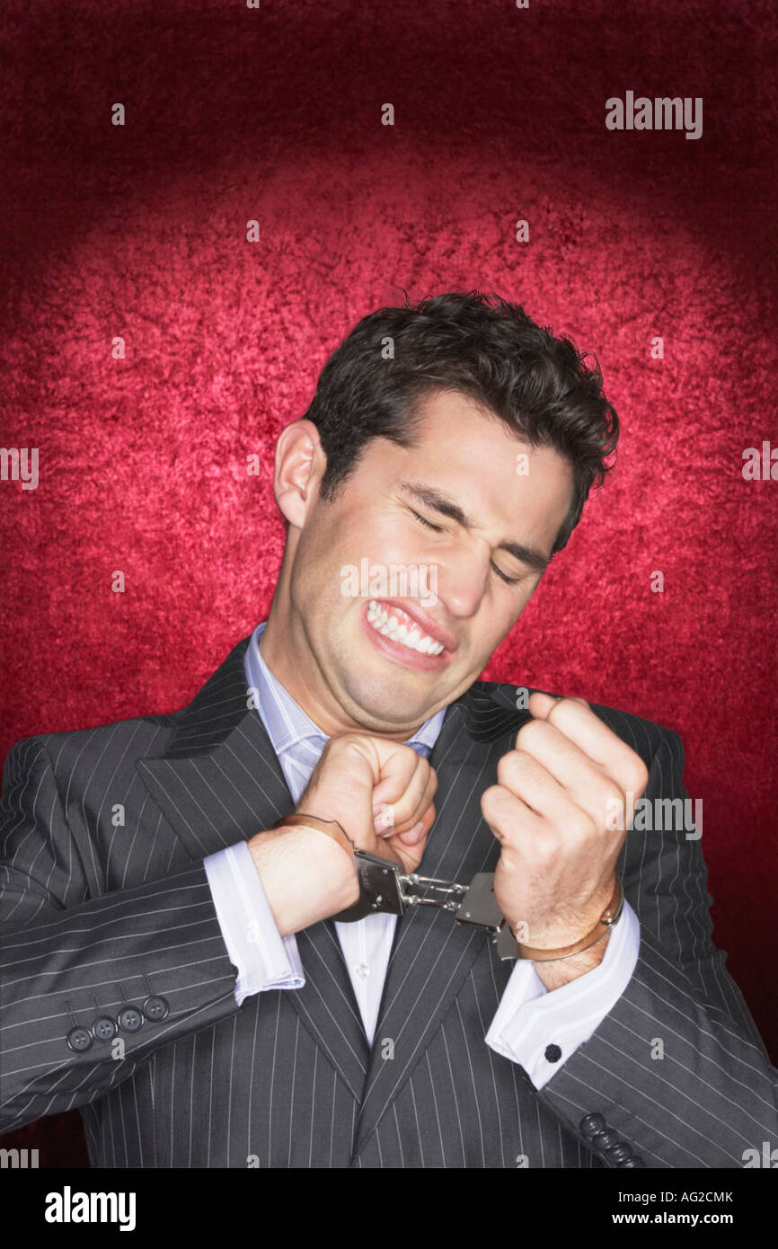Man straining in handcuffs against red velvet background Stock Photo ...