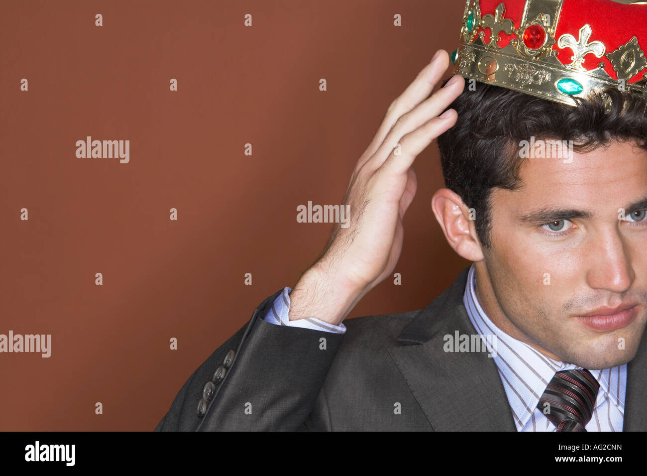 Man putting on crown against brown background, close-up Stock Photo - Alamy