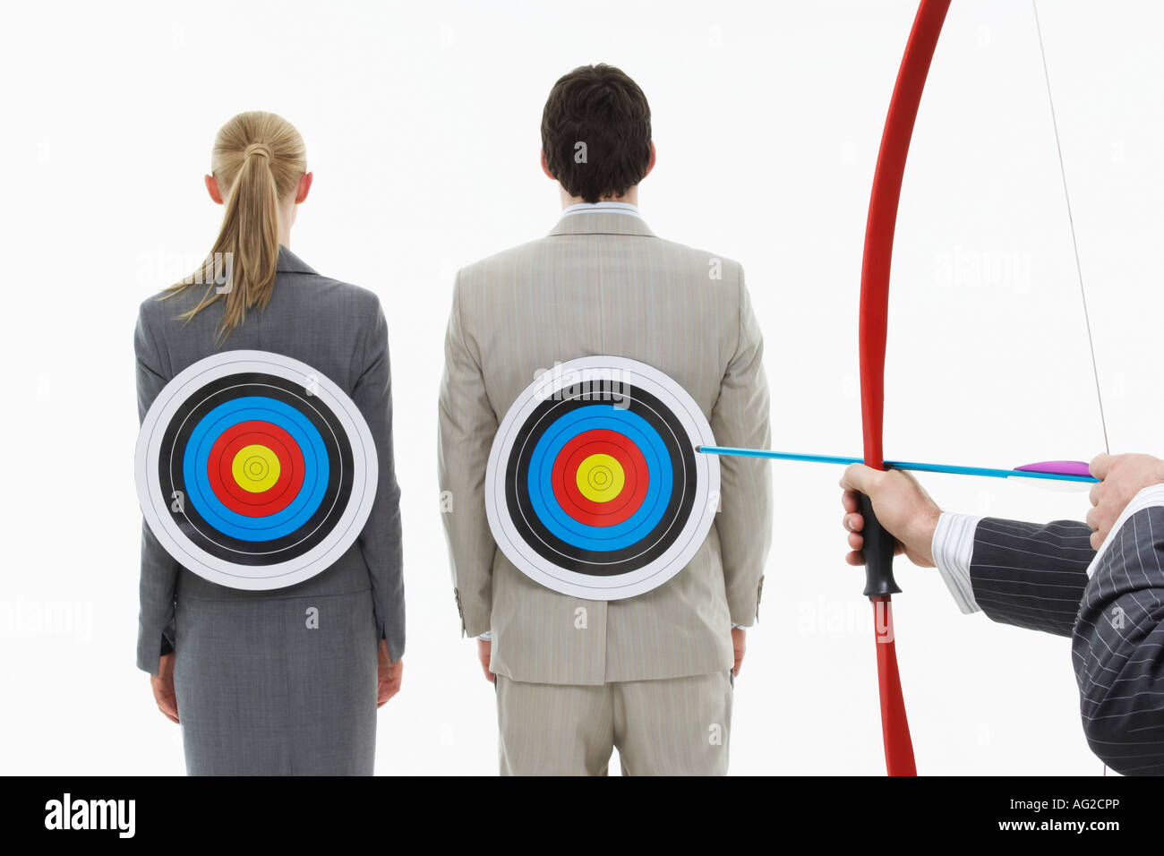 Two business people with targets on backs while man aims bow and arrow ...