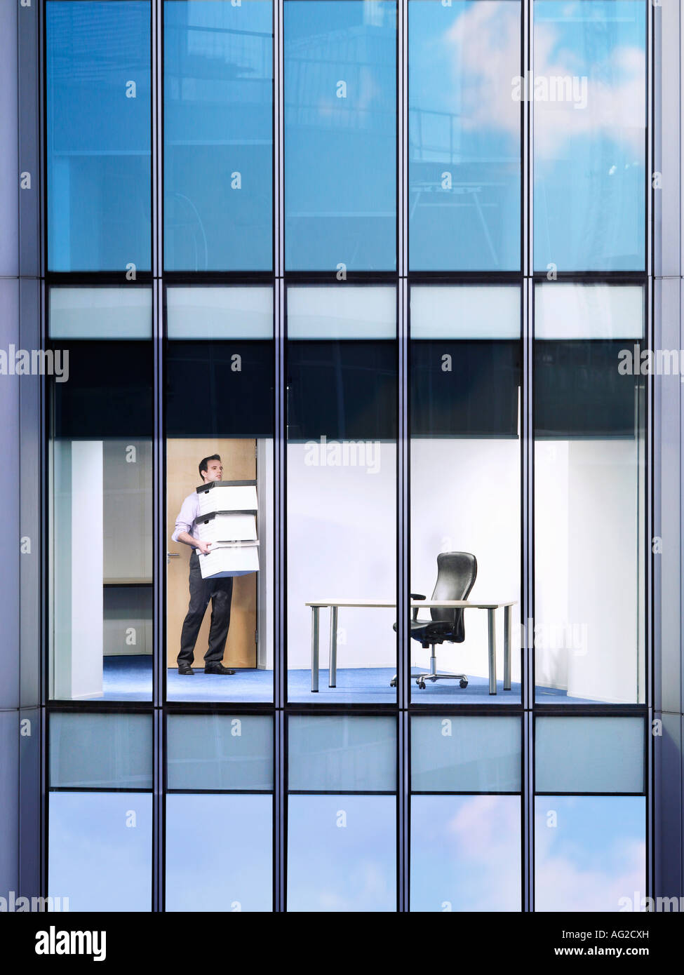 Office worker carrying boxes in office, view from building exterior ...