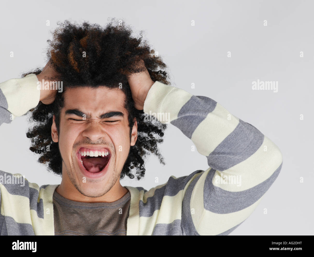 Young man with head in hands screaming Stock Photo - Alamy