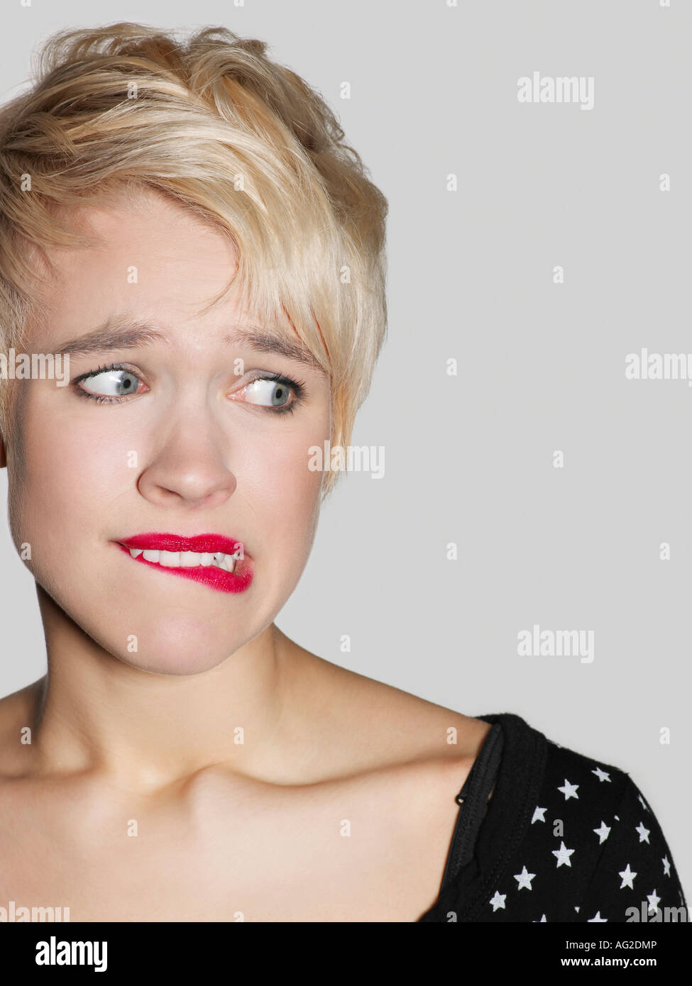 Young woman biting lip and looking to side, close-up Stock Photo - Alamy