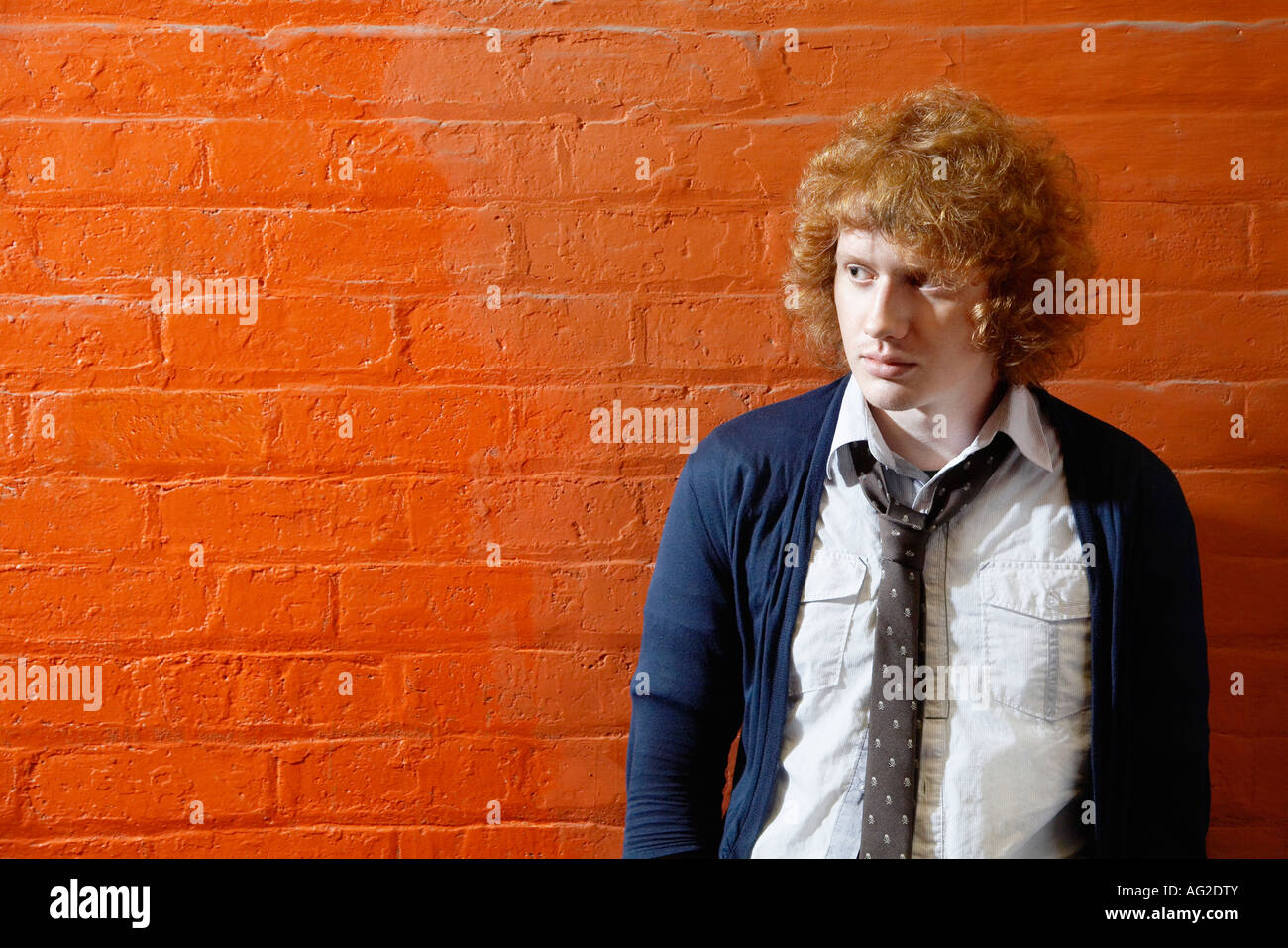 Young man standing in front of orange brick wall Stock Photo - Alamy