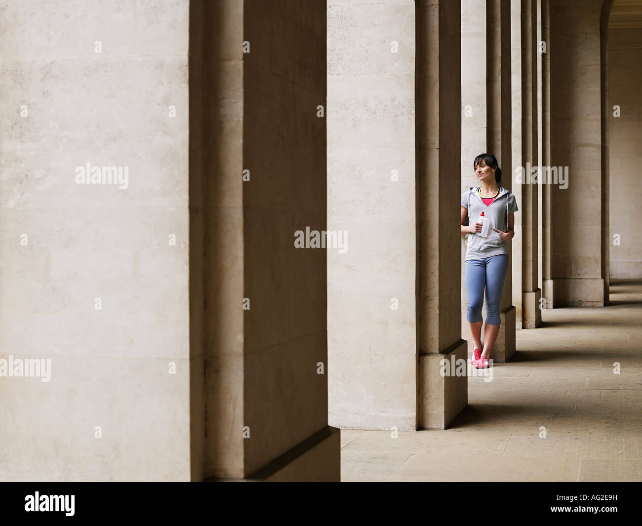 Woman standing against column in portico Stock Photo - Alamy