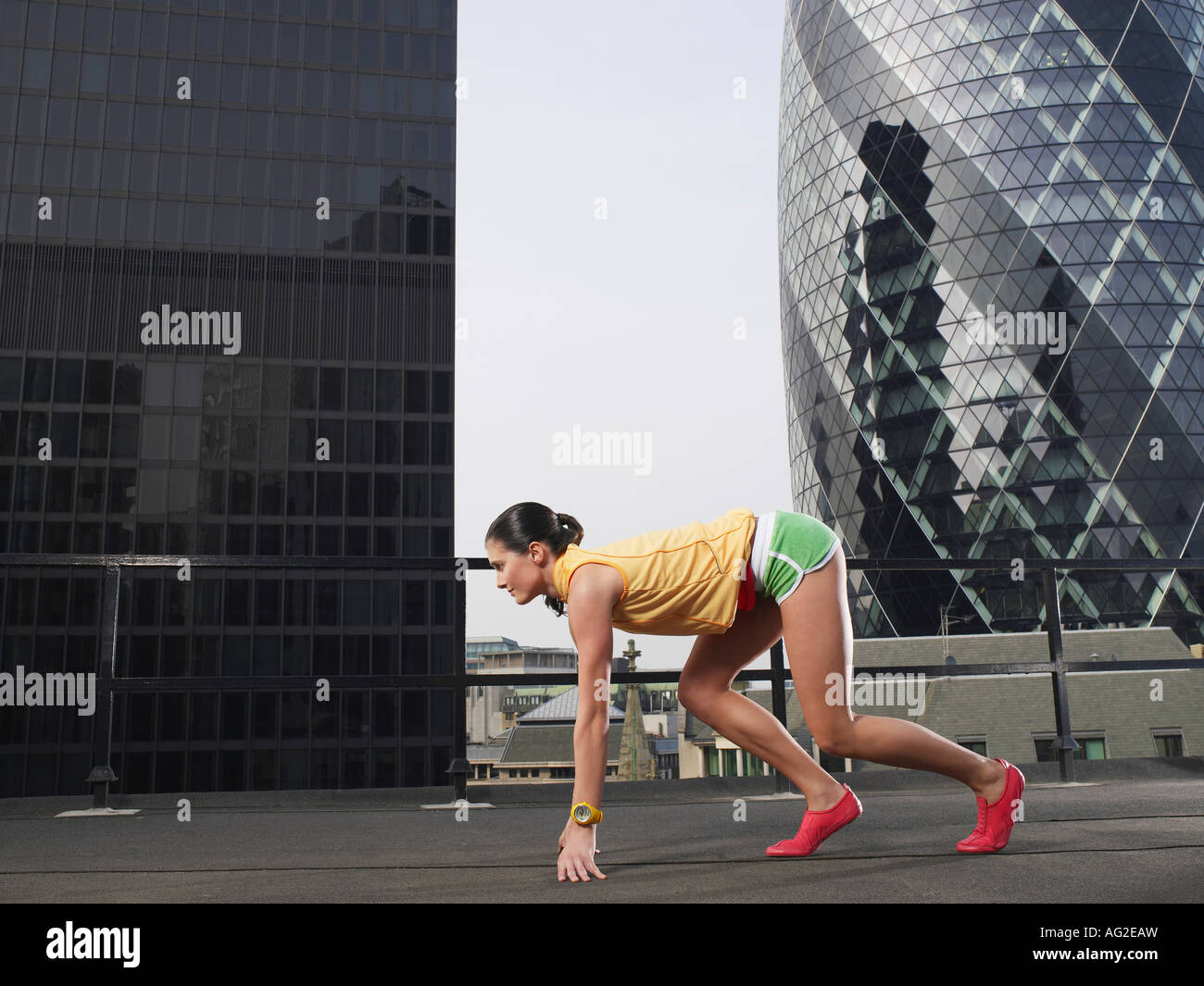 Woman crouching in starting position on downtown rooftop, side view ...