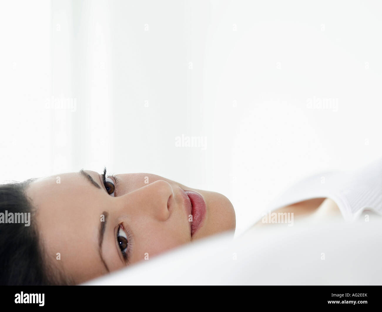 Young woman lying down, looking away, close-up Stock Photo - Alamy