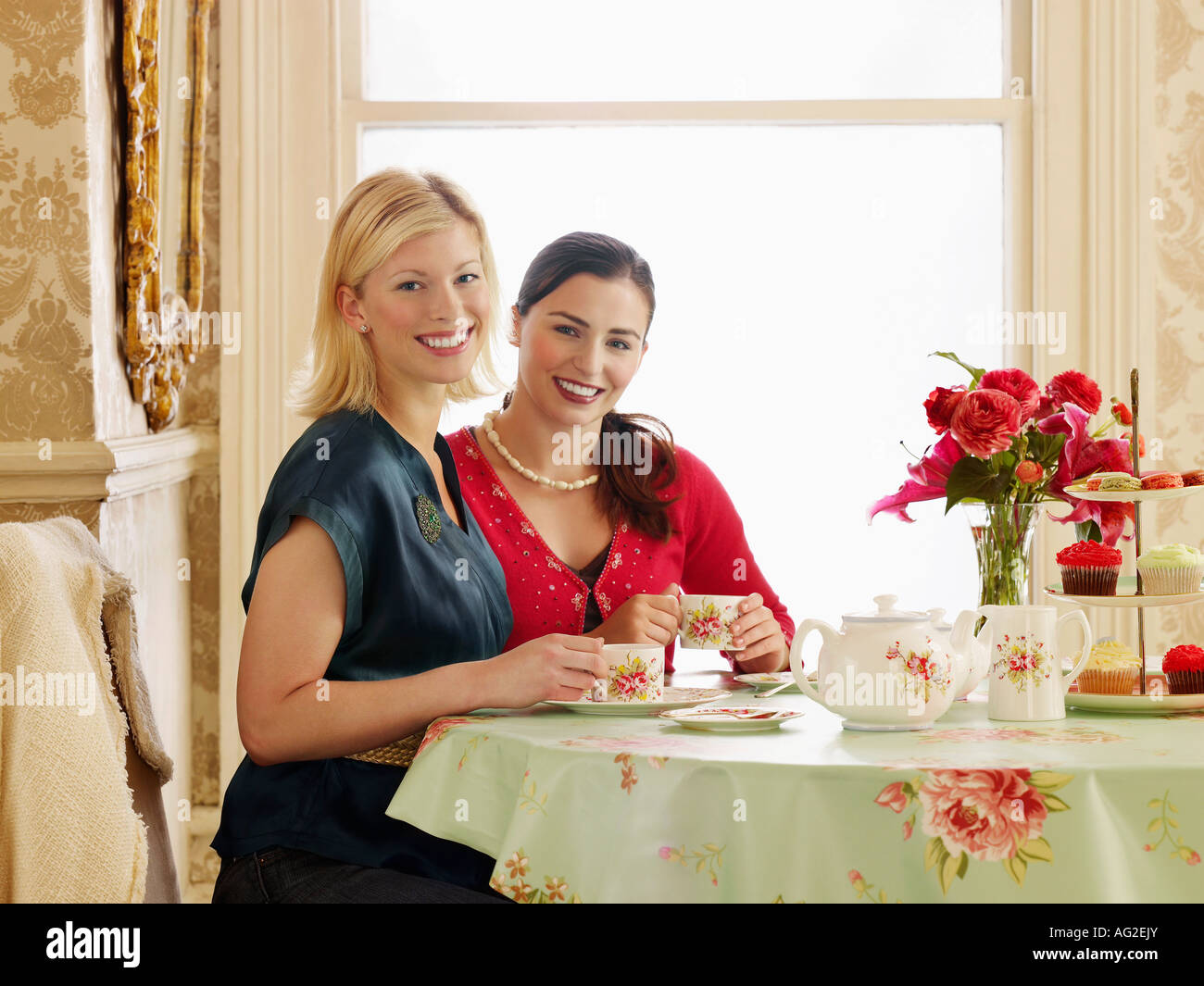 Two young women sitting at dining table drinking tea, portrait Stock ...