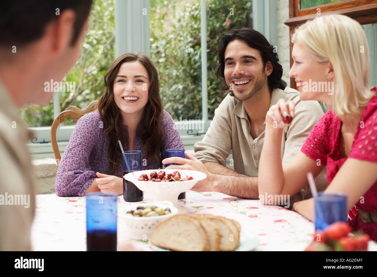 Group of young people sitting at verandah table, laughing Stock Photo ...