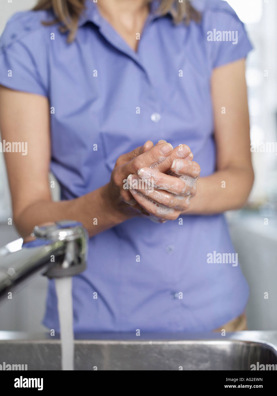 Woman washing hands in kitchen sink, mid section Stock Photo - Alamy