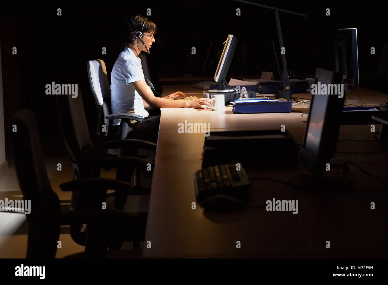 Woman working at laptop in dark office Stock Photo - Alamy
