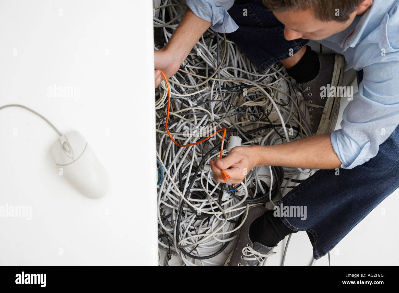 Man working on tangle of computer wires in office Stock Photo - Alamy