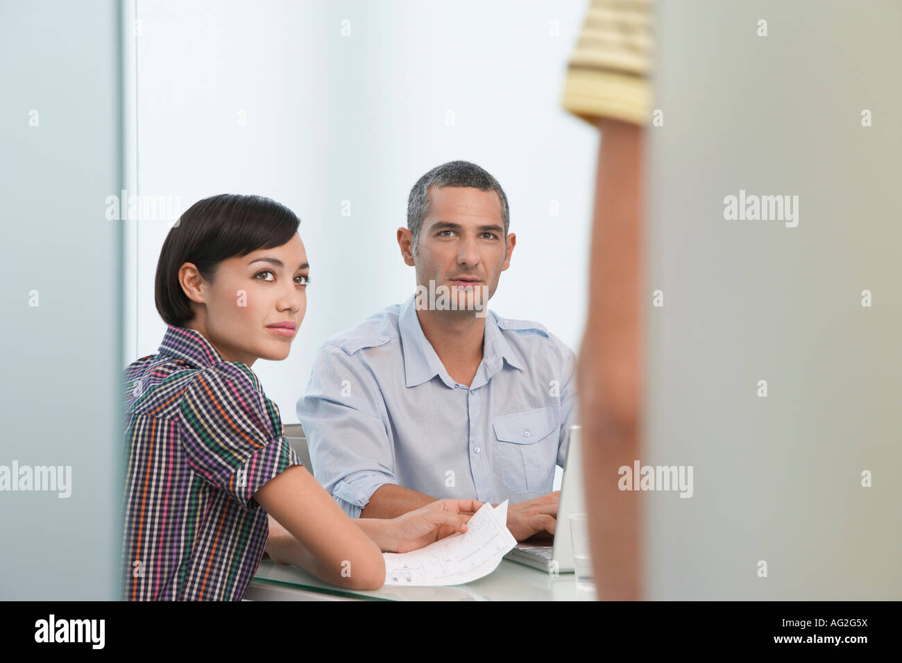 Two workers looking up at co-worker (mid section) standing in office ...