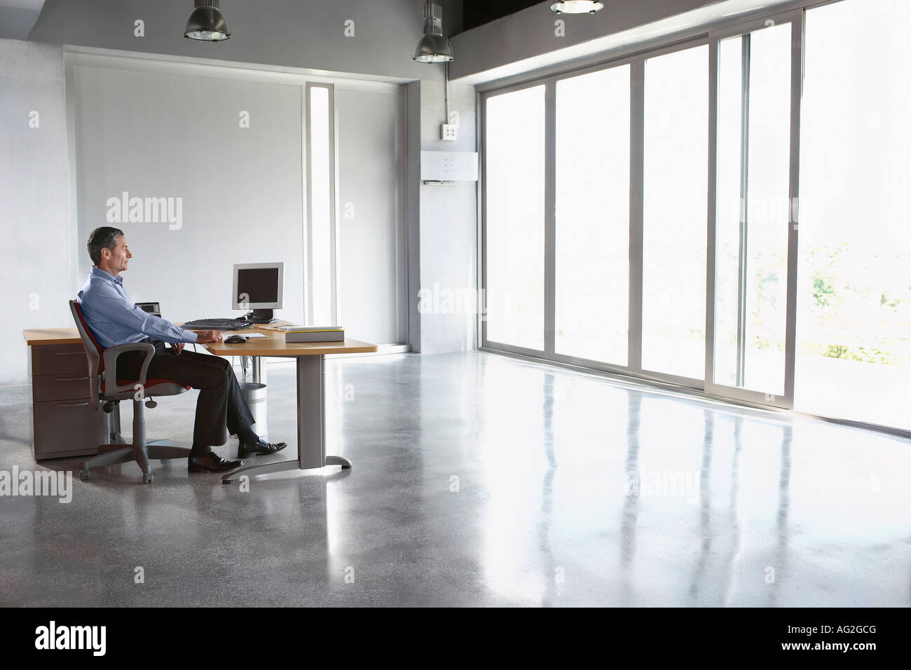 Man sitting at desk in empty office building Stock Photo - Alamy