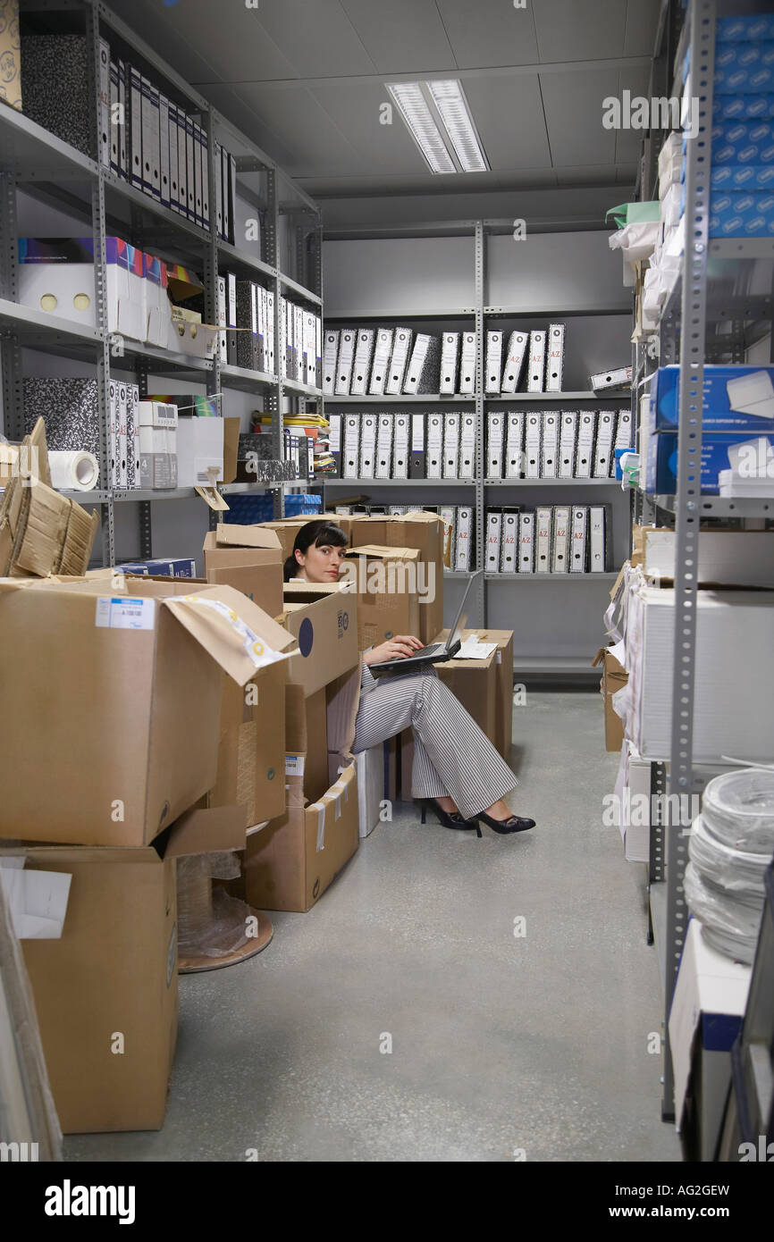 Woman using laptop, between boxes in storage room Stock Photo - Alamy