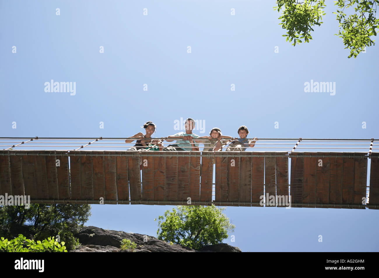 Parents and two sons (7-12) on bridge, looking down Stock Photo - Alamy