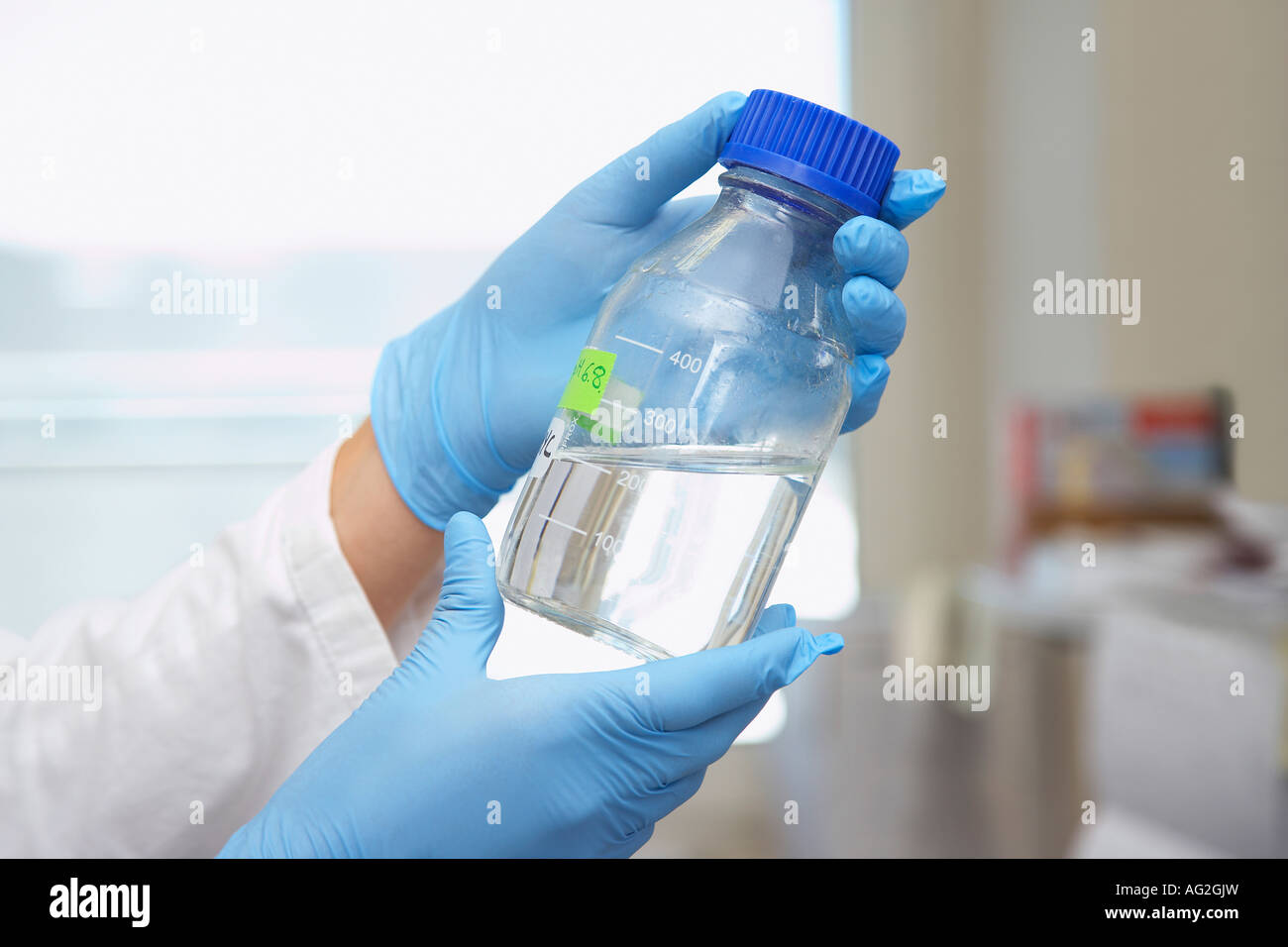 Chemist holding bottle of solution in laboratory, close-up of hands ...