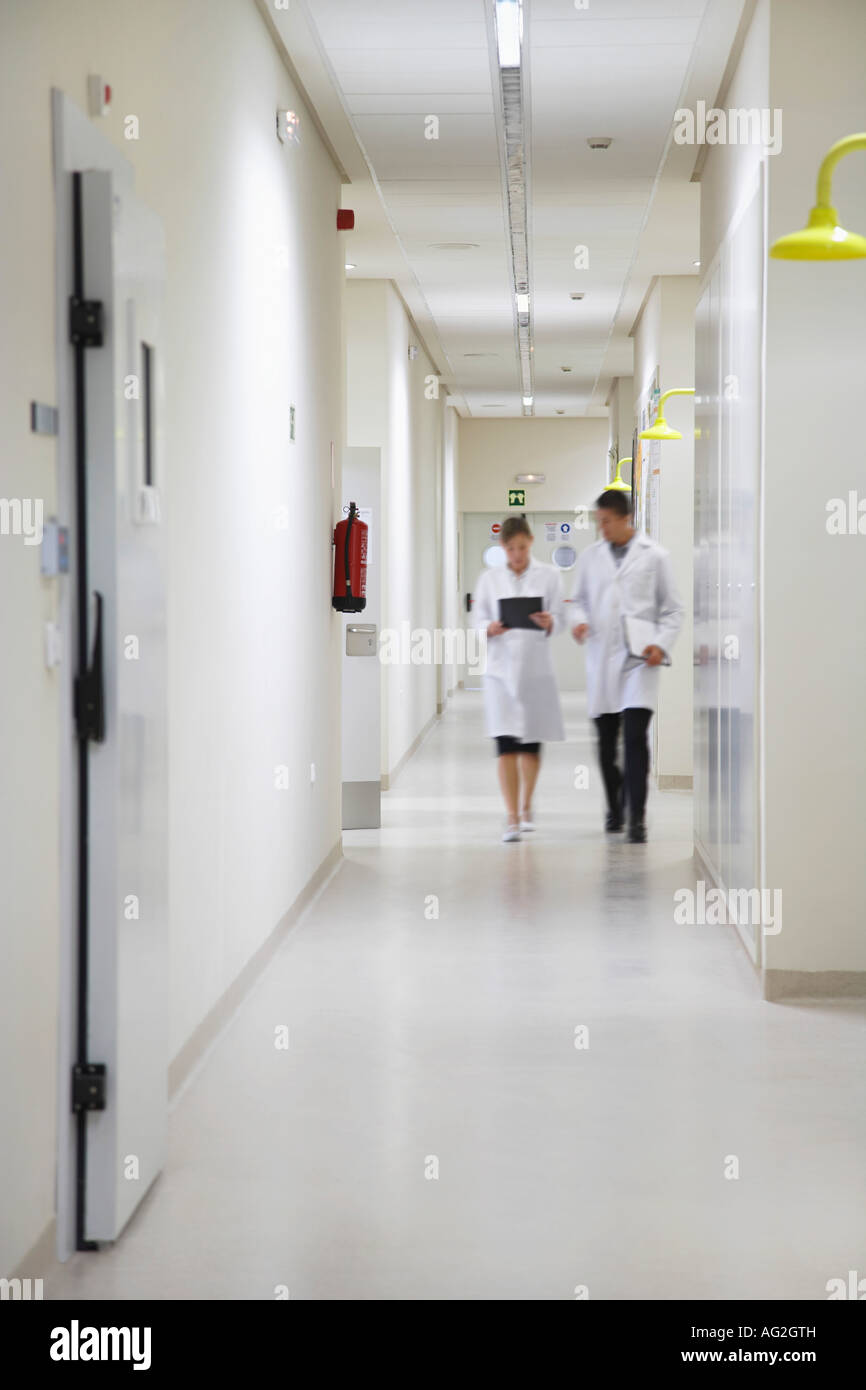 Two scientists walking down hallway Stock Photo - Alamy