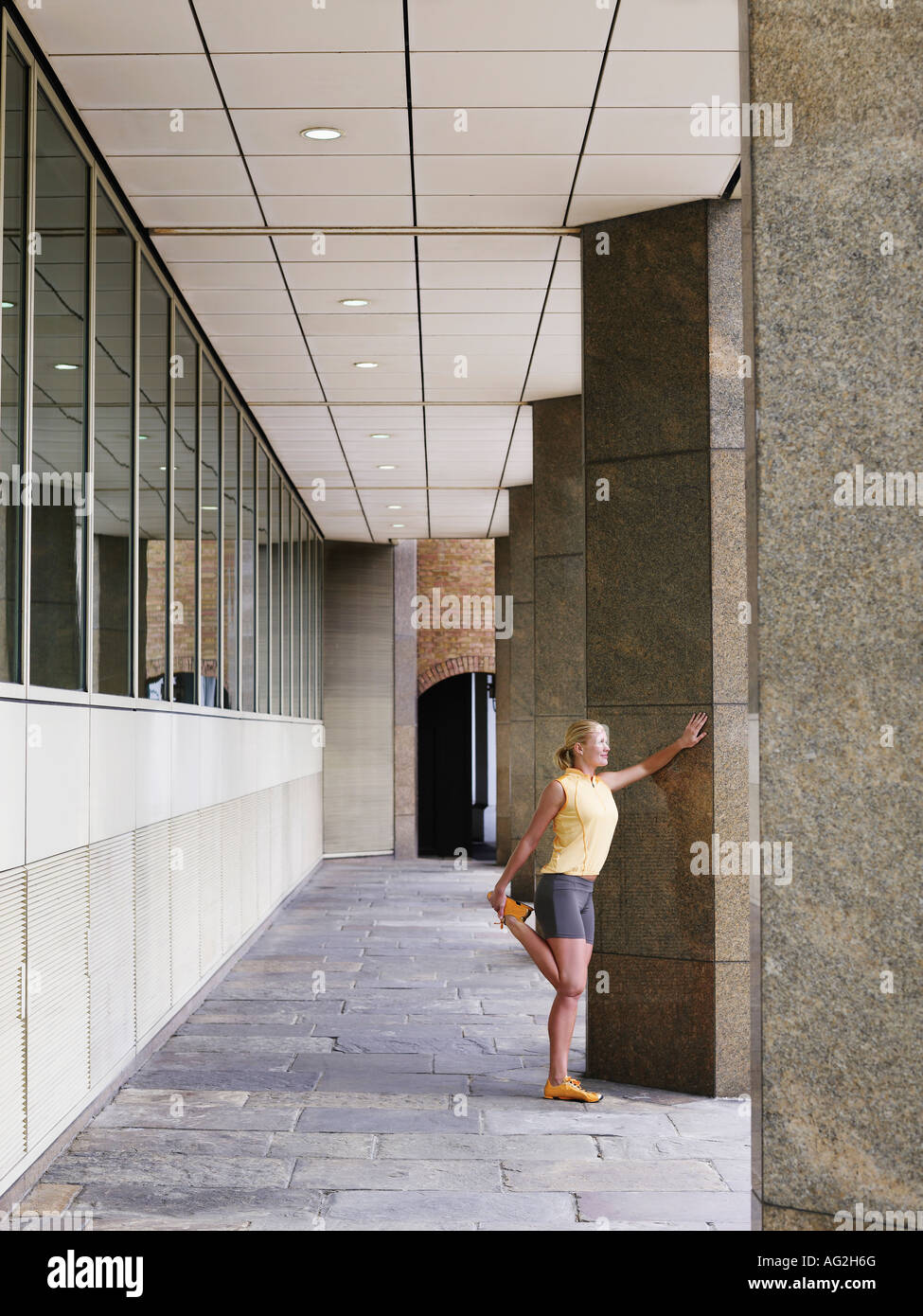 Woman stretching against a pillar Stock Photo - Alamy