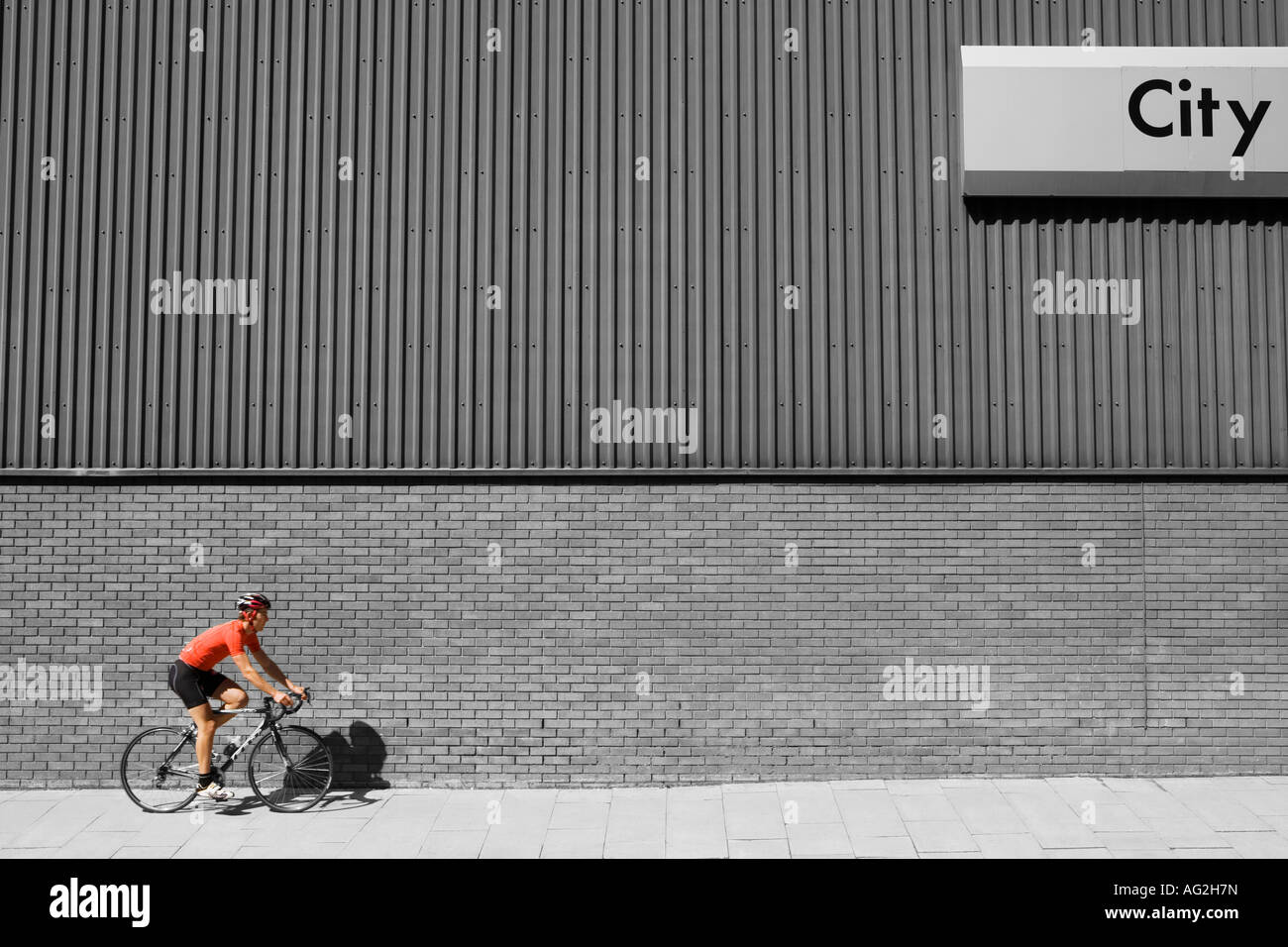 Man cycling past building with 'City' written on side Stock Photo - Alamy