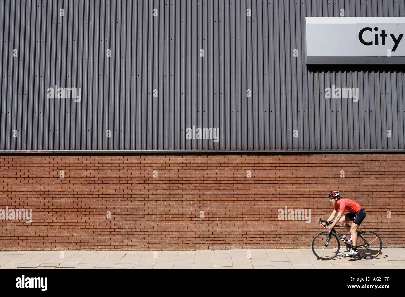 Man cycling past building with 'City' written on side Stock Photo - Alamy