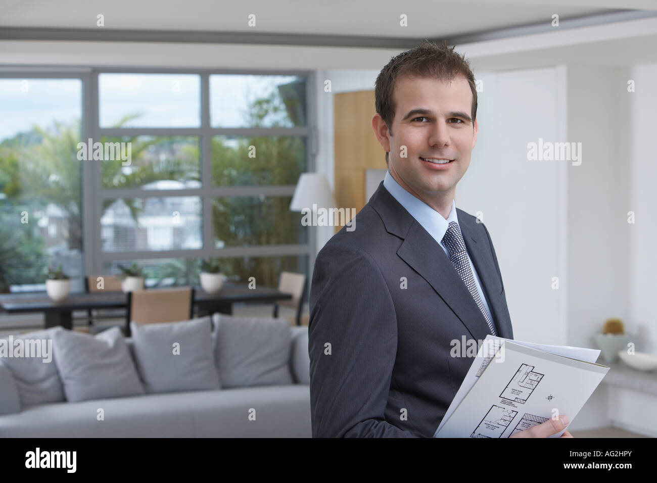 Male estate agent holding brochure in new home, portrait Stock Photo ...