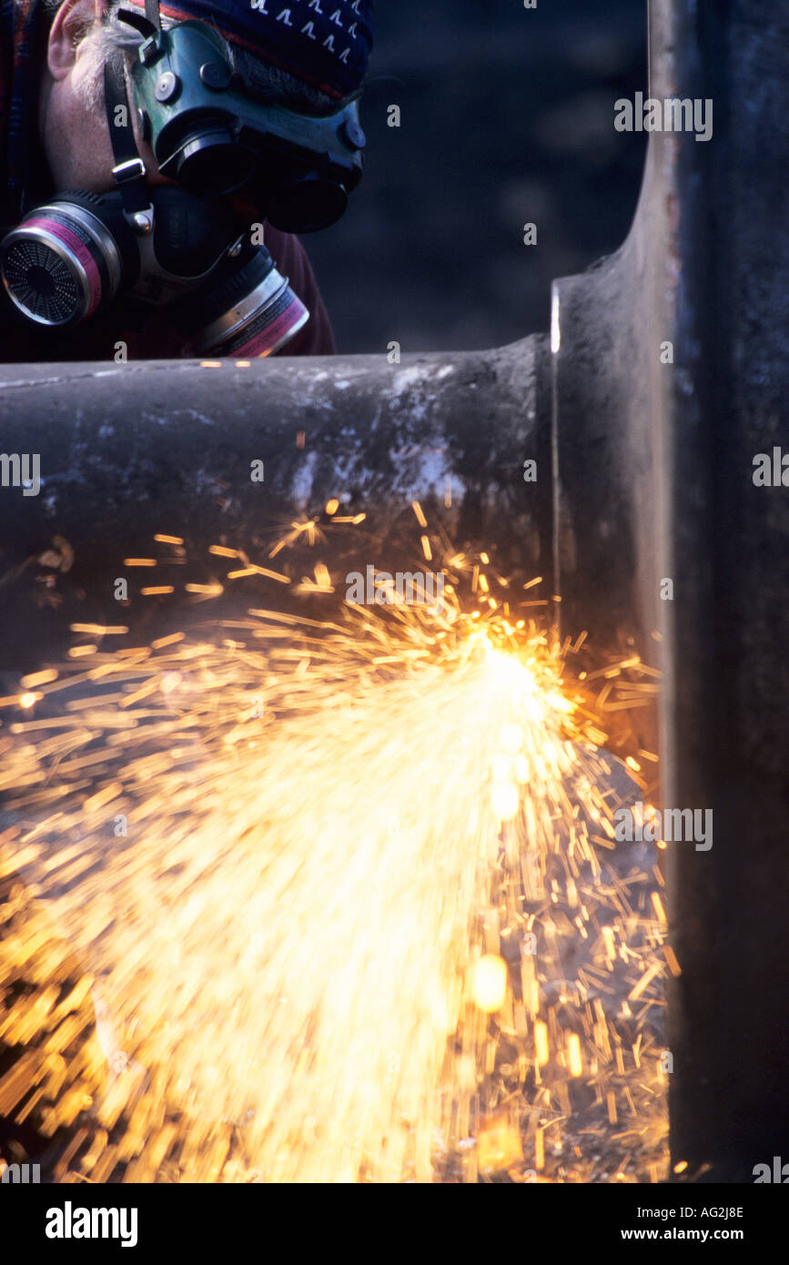 Railway worker using cutting torch on wheels at coal train wreck site ...