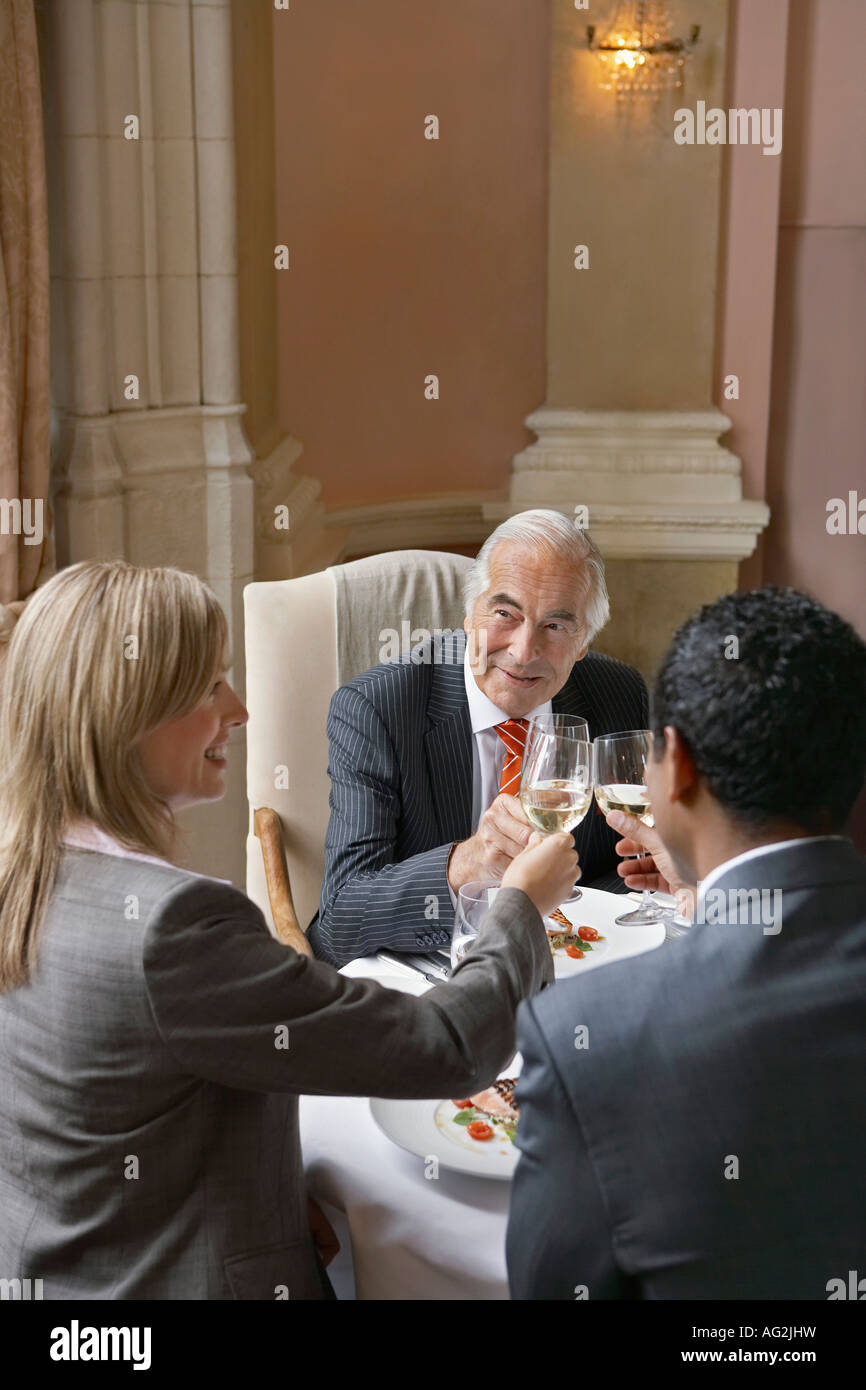 Three business people sitting at restaurant table, toasting Stock Photo ...