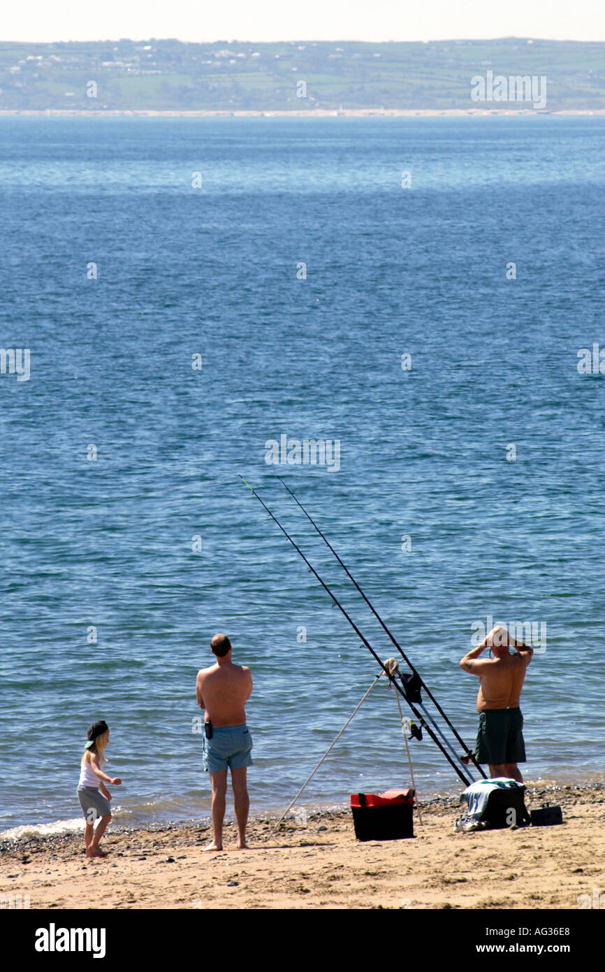 Tourists sea fishing on the beach in summer sunshine at Pwllheli ...