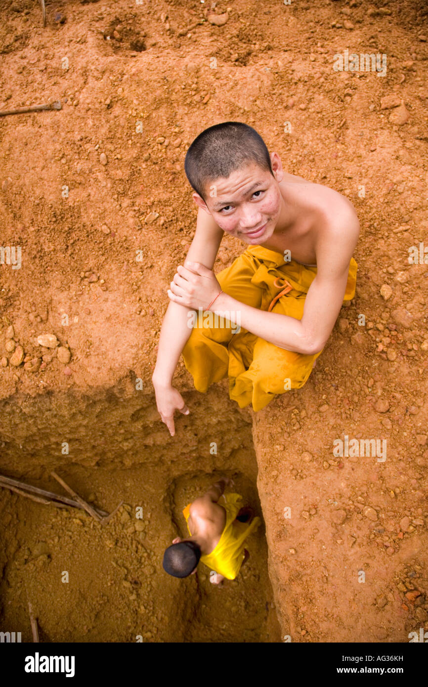 Monk watches another monk digging a hole at Wat Kang Vang Vieng Laos ...