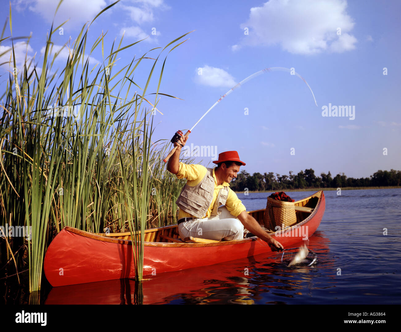 man netting fish from canoe in lake Stock Photo - Alamy