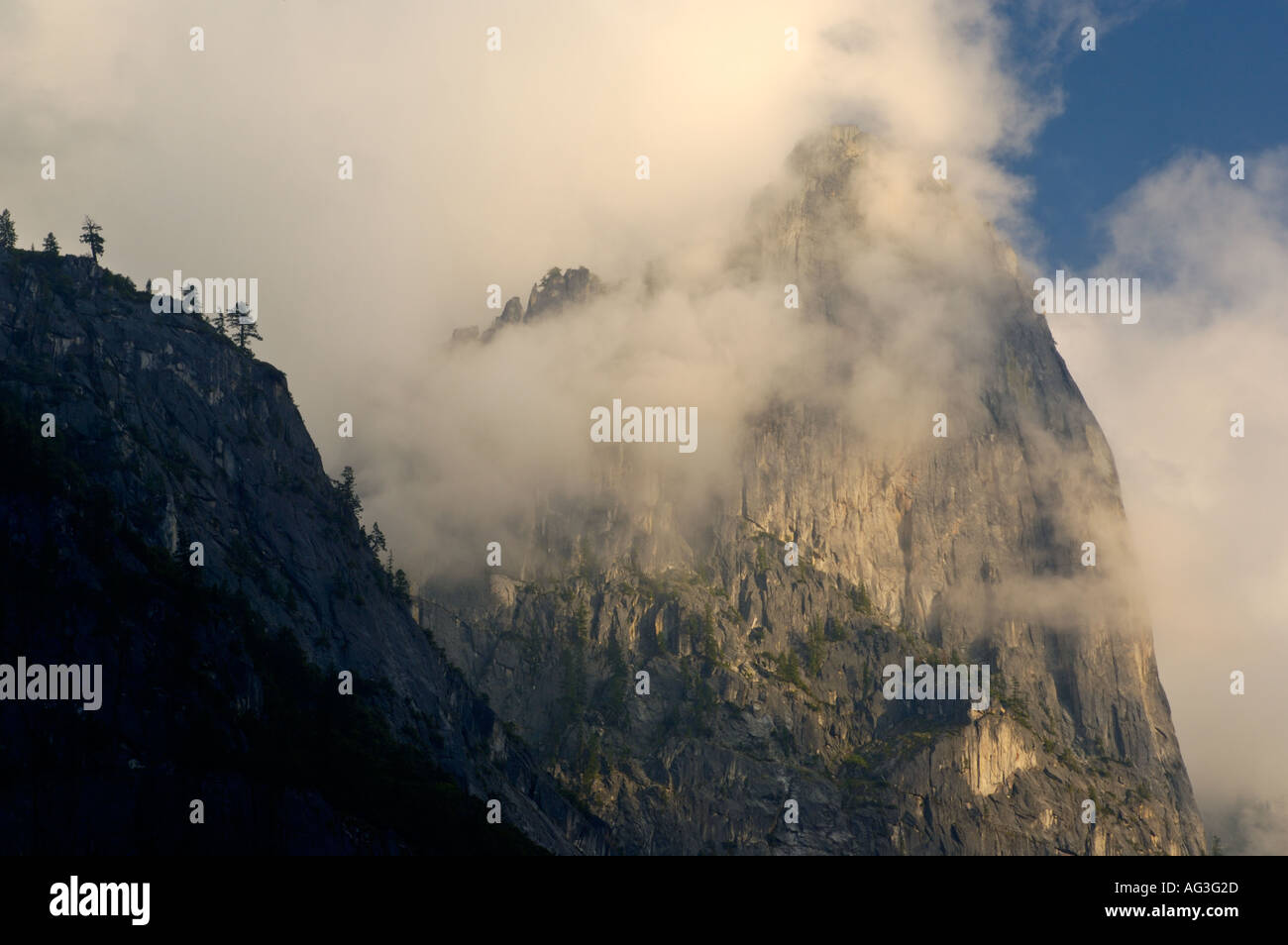 Storm clouds at sunset shroud the sheer cliff walls of Sentinel Rock ...