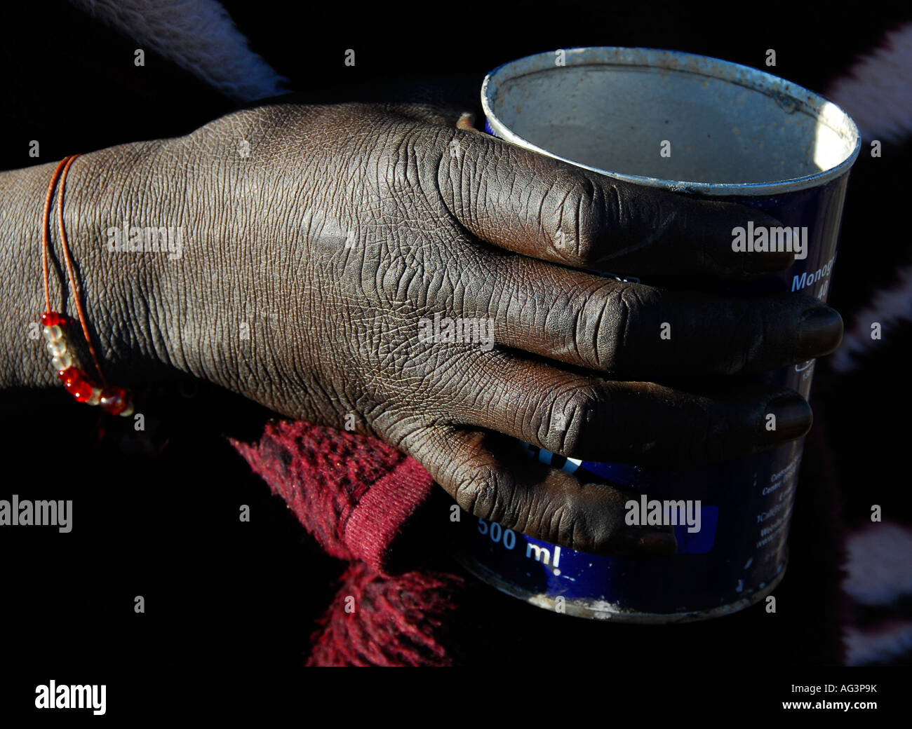 Close-up view of gnarled African hand holding old tin can as a coffee ...