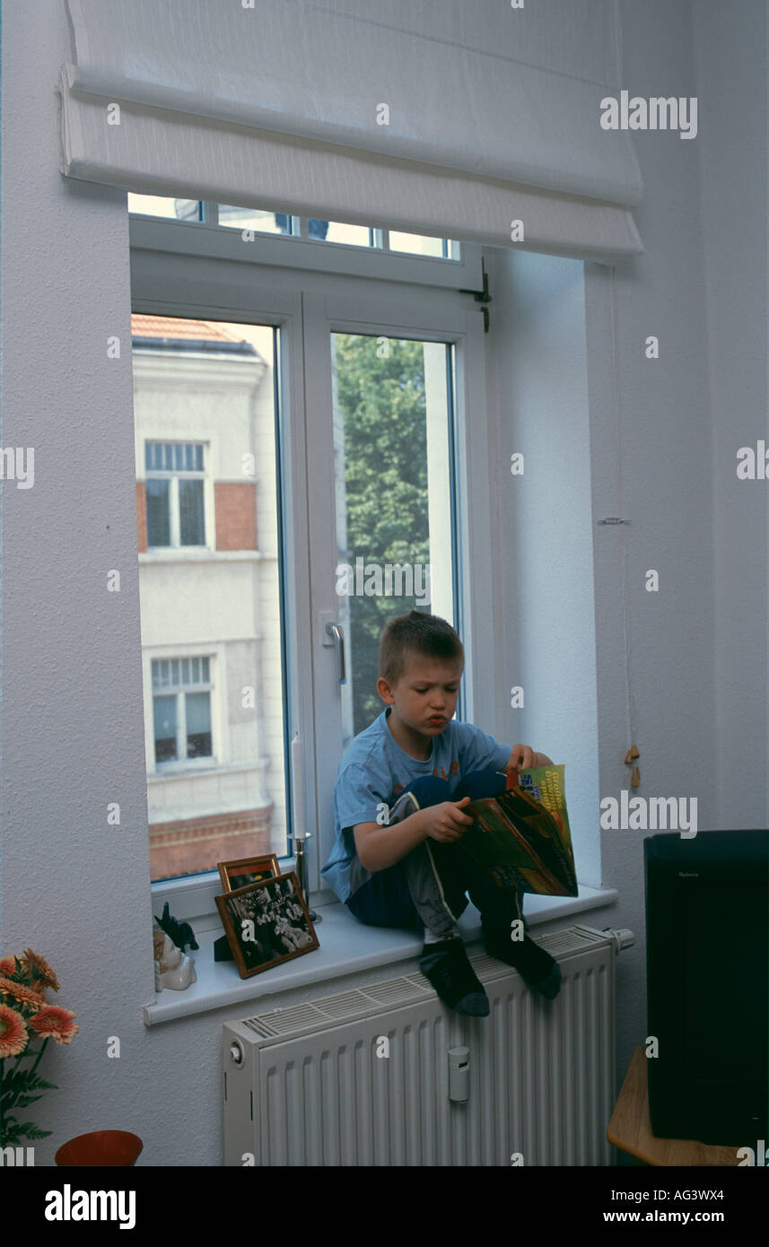 Boy sitting in the window frame Stock Photo - Alamy