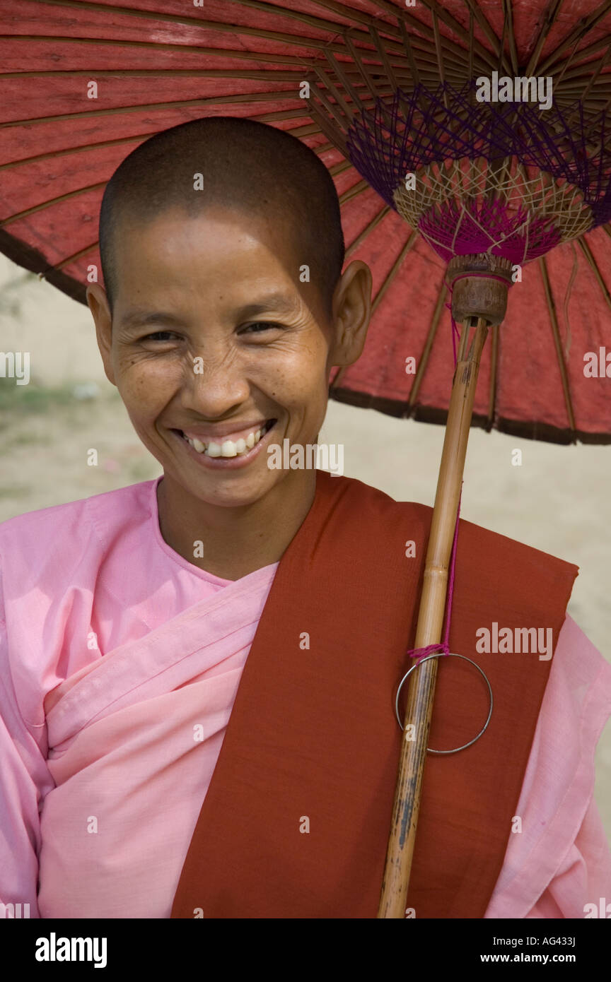 Female monk with shaved head and umbrella at Mingun Paya near Mandalay ...