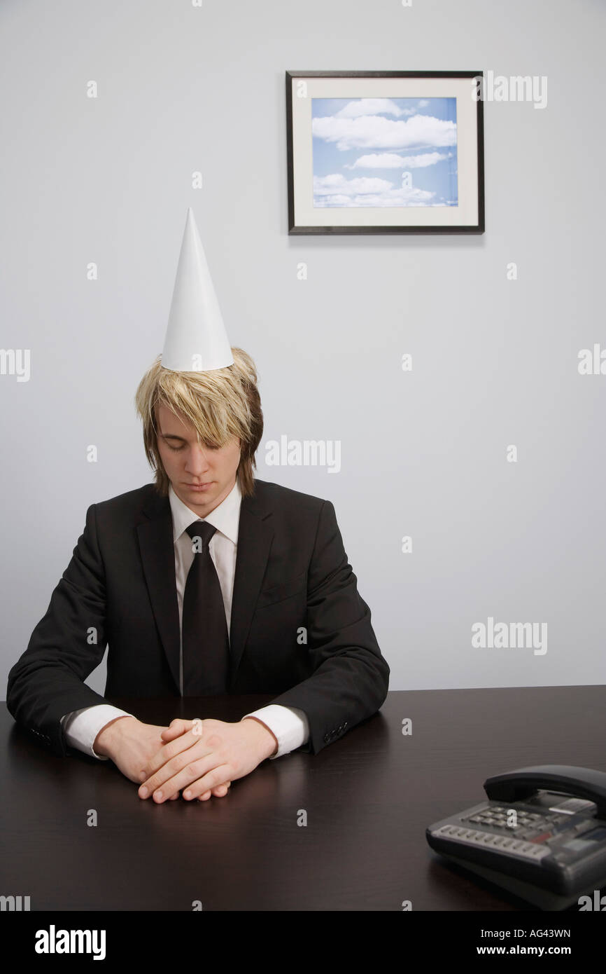 Businessman wearing a dunce cap Stock Photo - Alamy