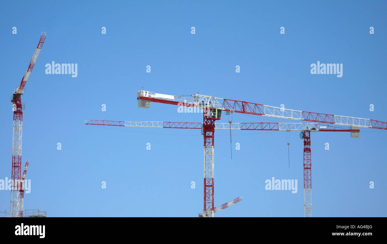 Red and White construction cranes against blue sky Stock Photo - Alamy