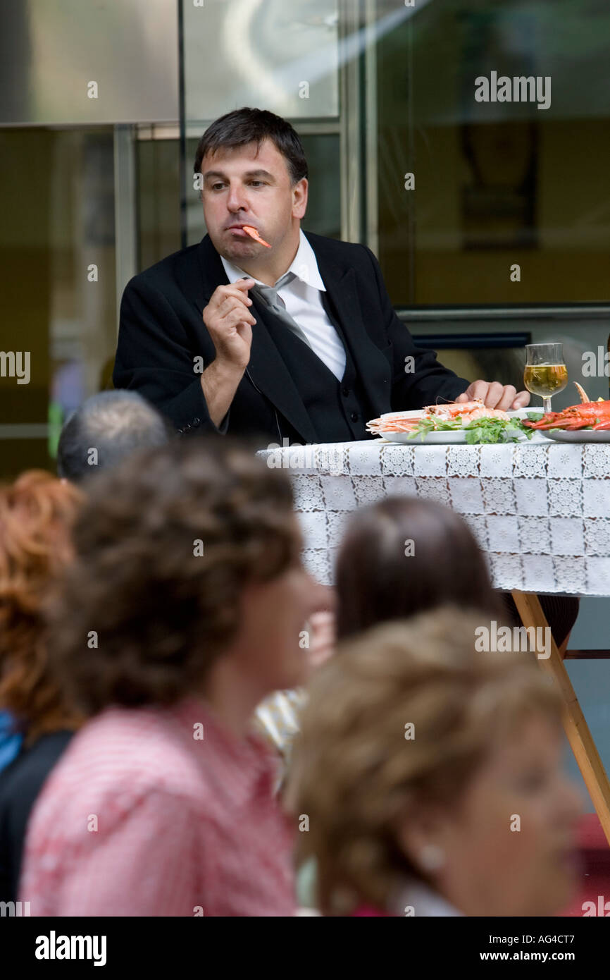 Male comedian dining in a busy street as pedestrians walk past Bilbao ...