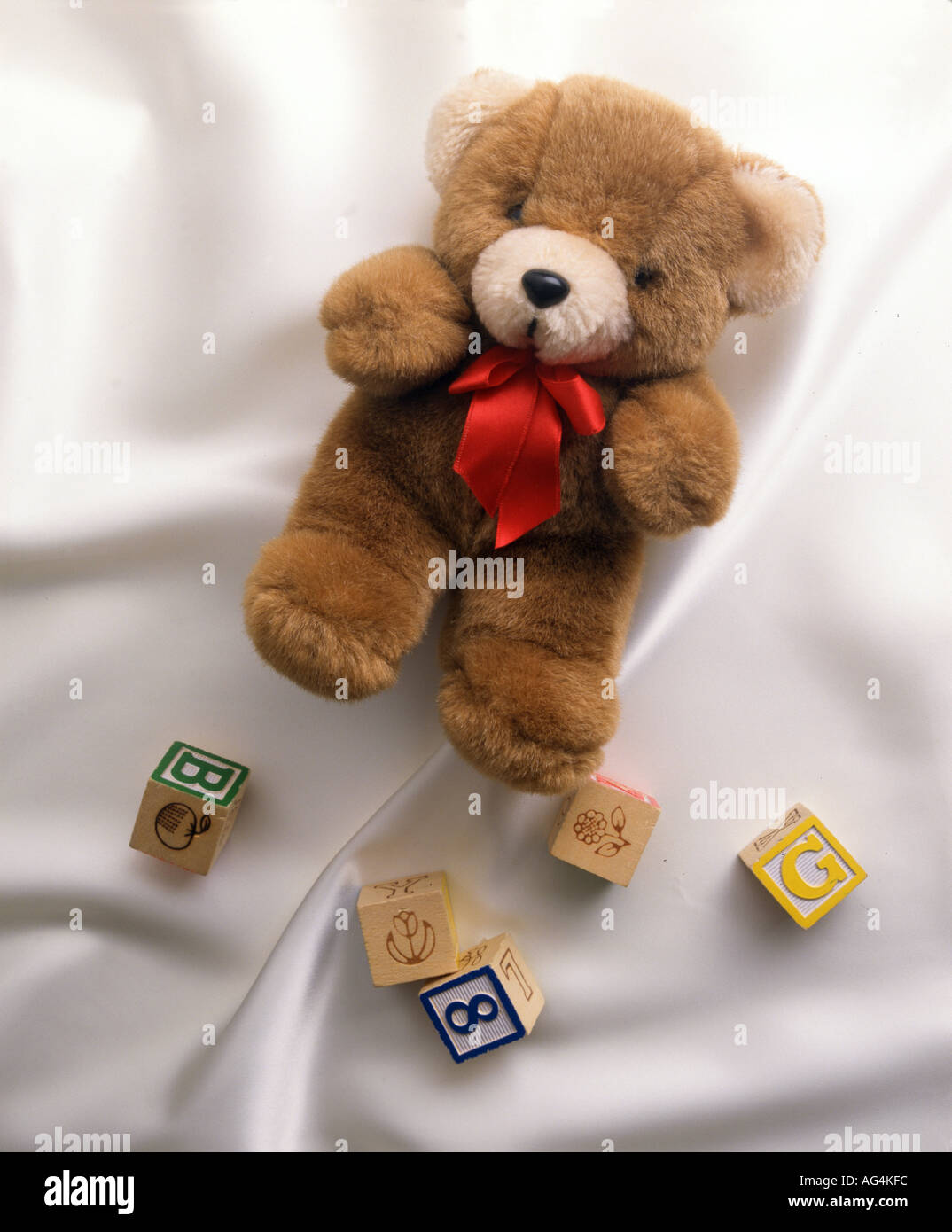 Child s teddy bear and play blocks on a white satin background Stock ...