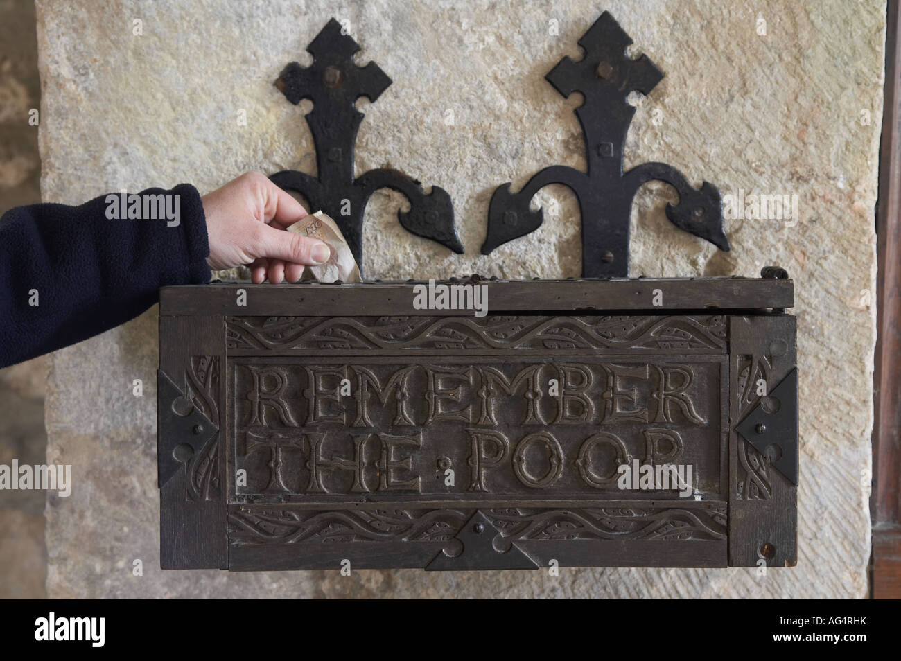 Historic wall-mounted alms or poor box close-up (person's hand putting ...