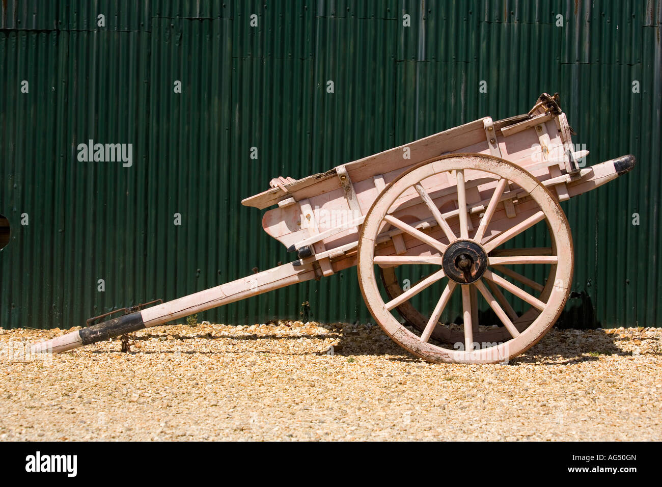 Wooden farm cart standing on gravel outside green corrugated iron bard ...
