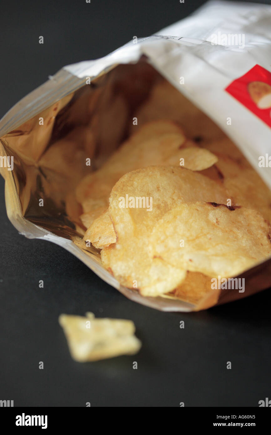 Open packet of crisps / chips on black background Stock Photo - Alamy