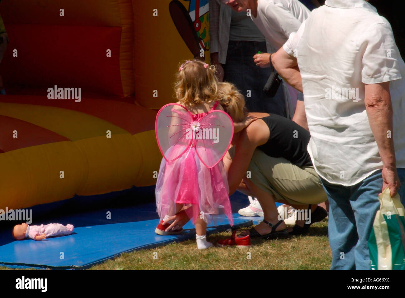 Little girl in angel fancy dress about to go and play on bouncy castle ...