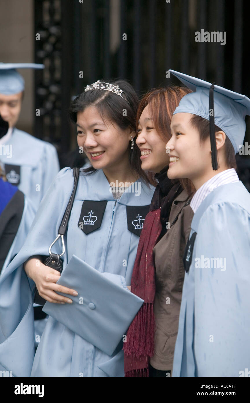 Asian graduate in costume and mortar boards pose with friends during ...
