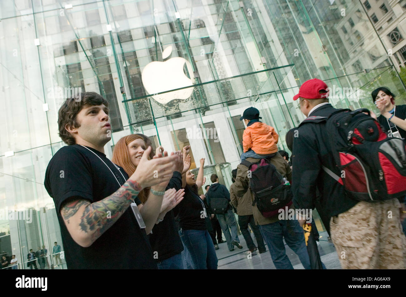 Apple employees cheer to welcome clients entering the Apple store cube ...