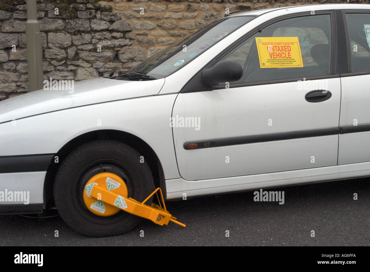 White car with DVLA wheel clamp and notice Stock Photo - Alamy