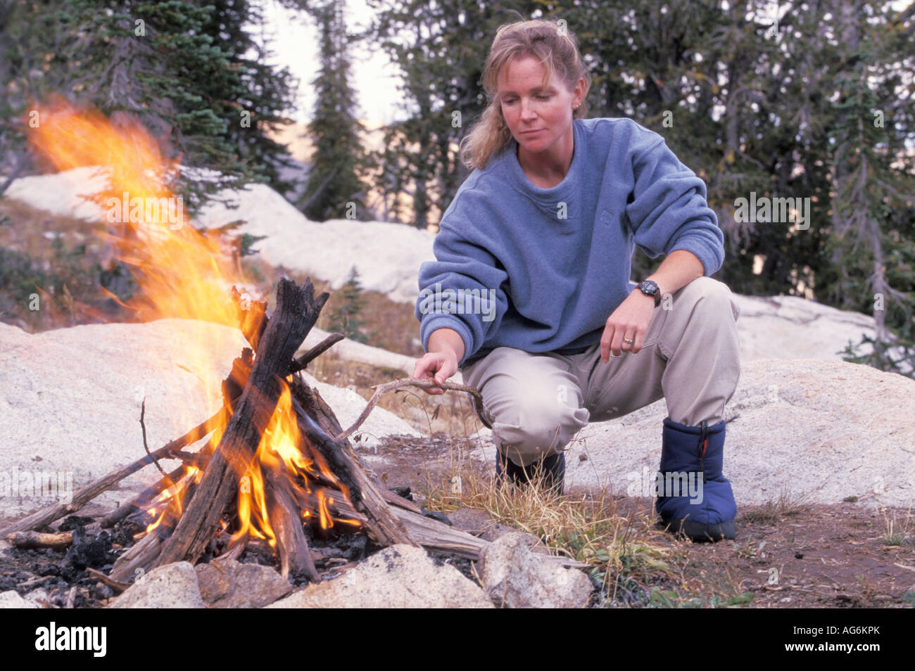 Caucasian Woman Stoking A Fire In The Wilderness Stock Photo - Alamy