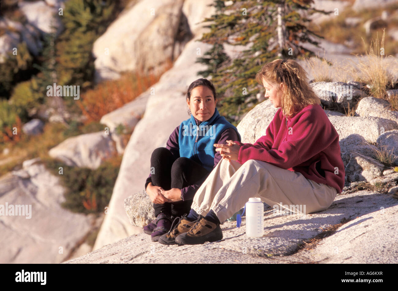 Two Female Hikers Sitting On A Rock And Resting Together Stock Photo ...